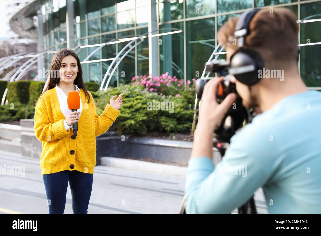 Young journalist and video operator working on city street Stock Photo ...