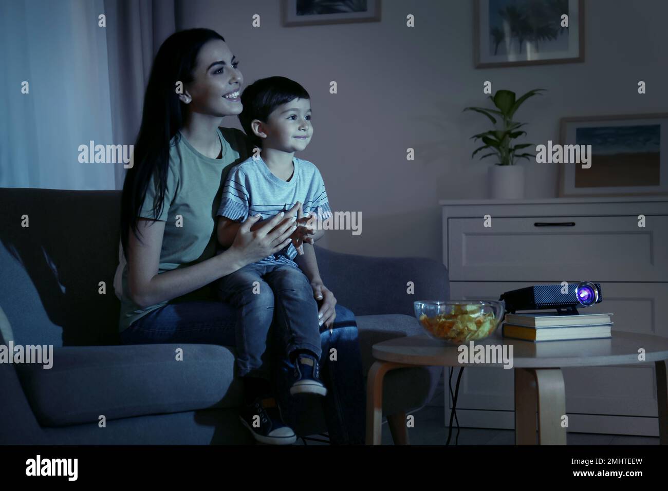 Young mother and her son watching movie using video projector at home ...