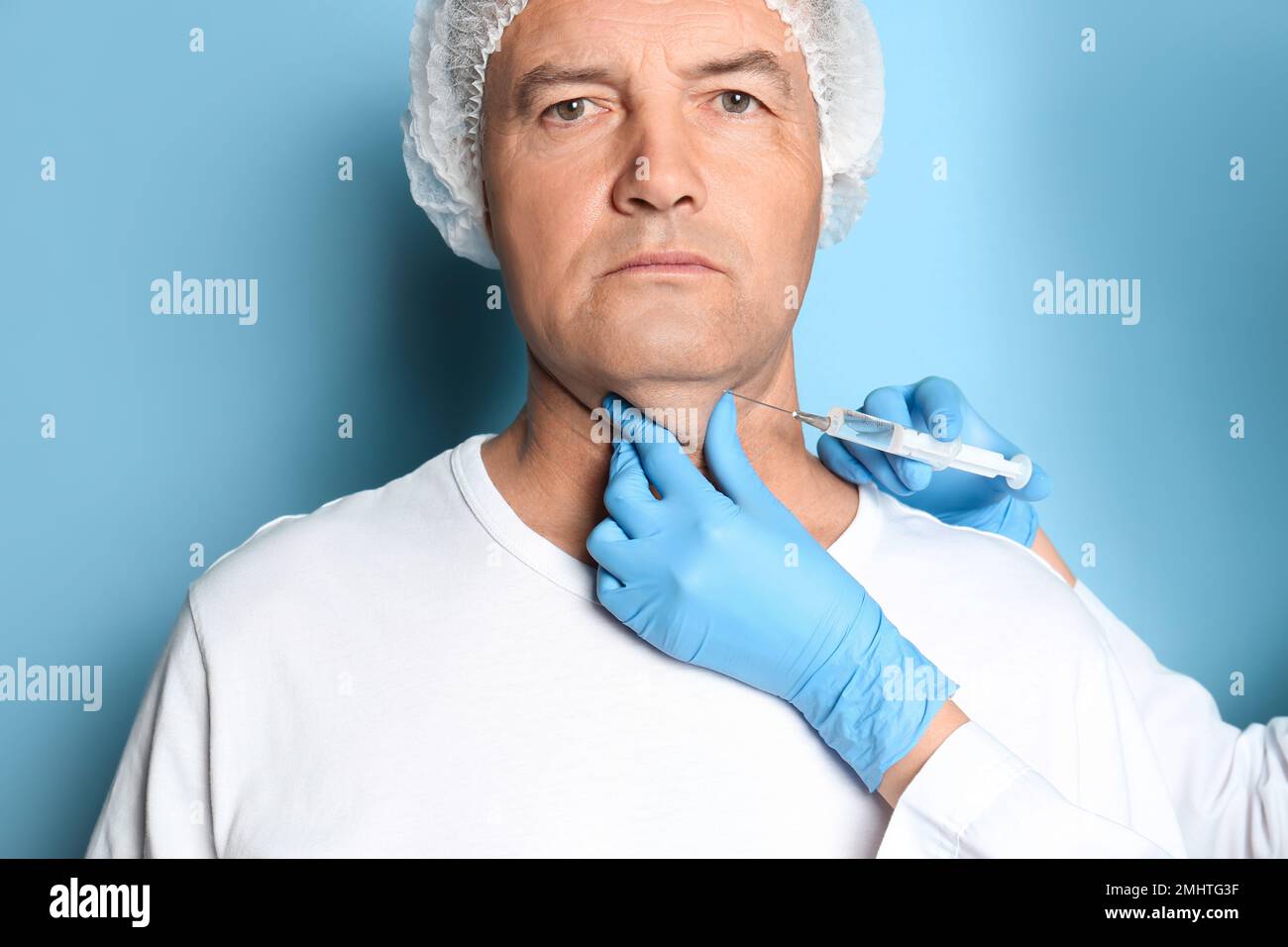 Mature man with double chin receiving injection on blue background ...