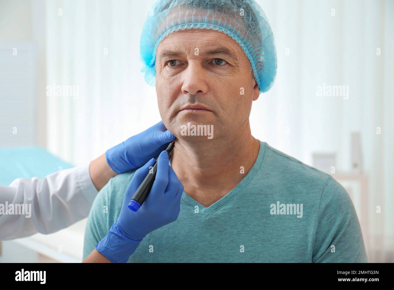 Surgeon with marker preparing man for operation in clinic. Double chin ...