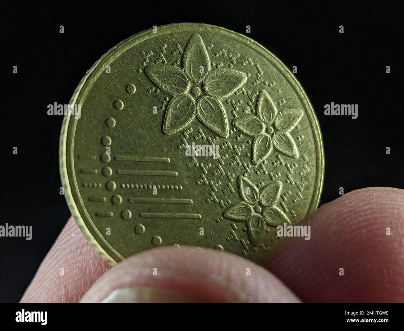 Closeup finger holding 20 cent Malaysia coin on a black background ...