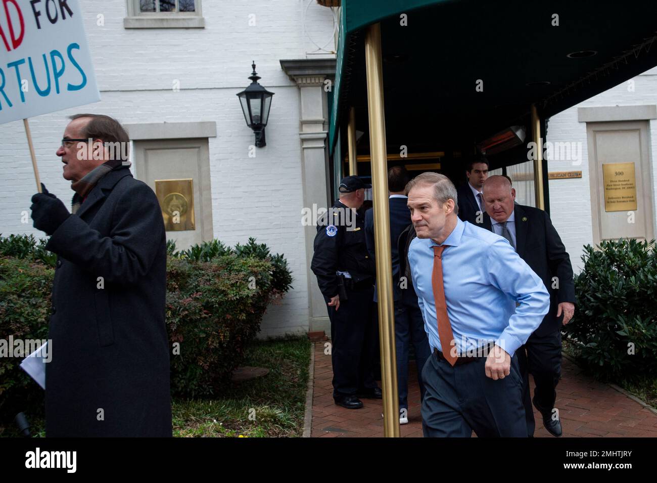 While a man holds a sign protesting United States Representative ...