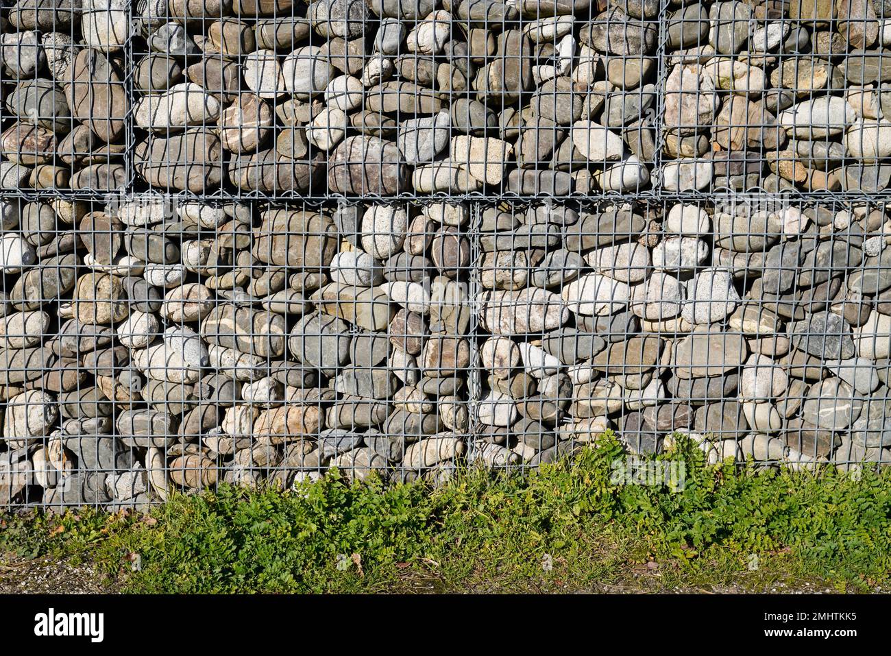 stone textured fence on green lawn made of mesh and stones background ...