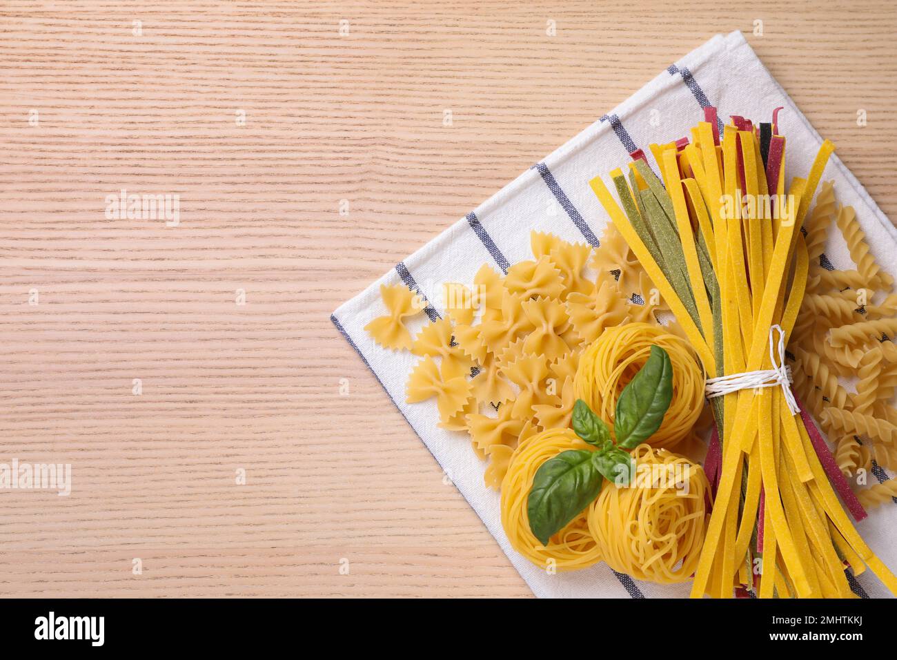 Different types of pasta on wooden table, top view. Space for text ...