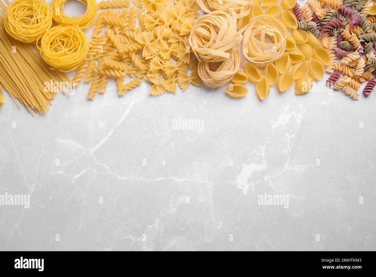 Different types of pasta on light grey marble table, flat lay. Space ...