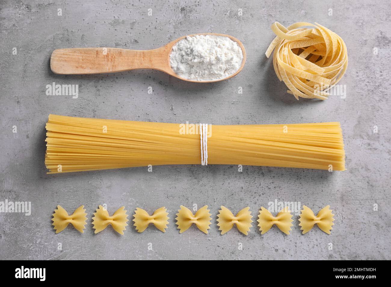 Flat lay composition with different types of pasta on grey background ...