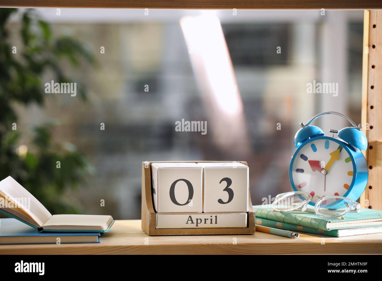 Wooden block calendar and alarm clock on shelf indoors Stock Photo - Alamy