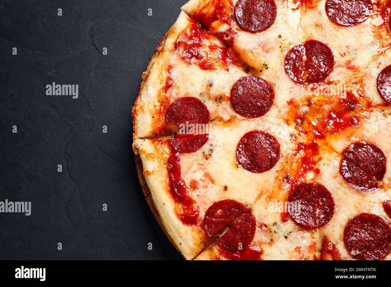 Hot delicious pepperoni pizza on dark table, top view. Space for text ...