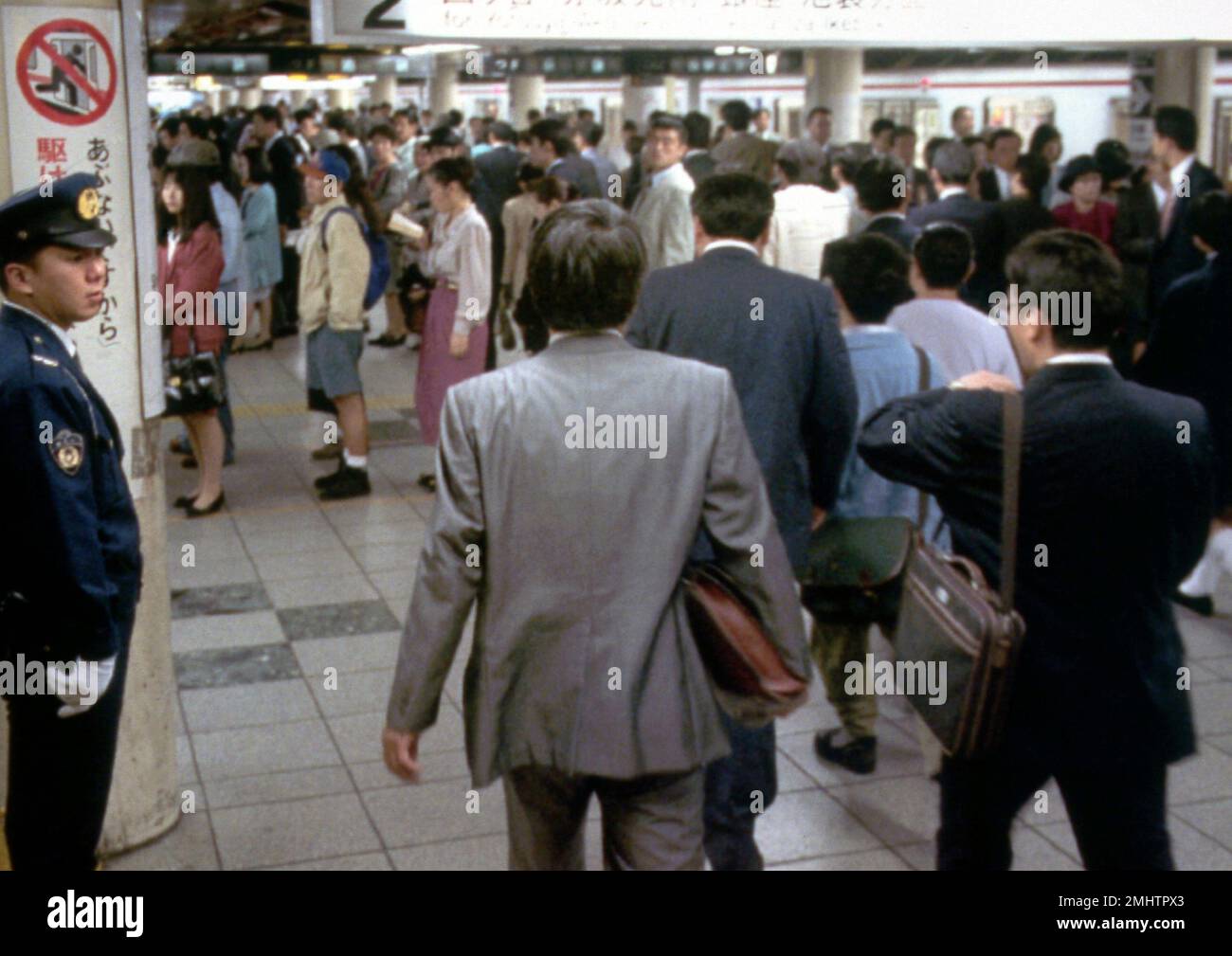 Commuters come and go as a police officer stands on guard at Tokyo's ...