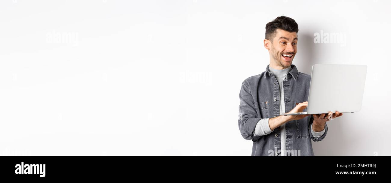 Man watching funny video on laptop, laughing at computer screen and ...