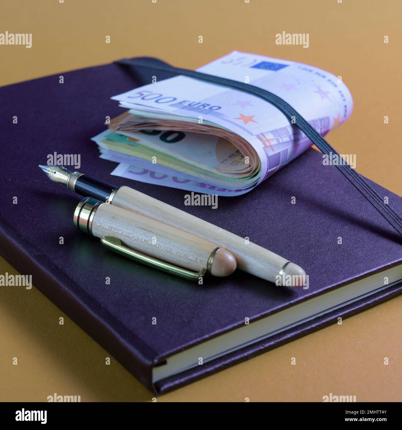 Euro banknotes, fountain pen and accounting black book on colored ...