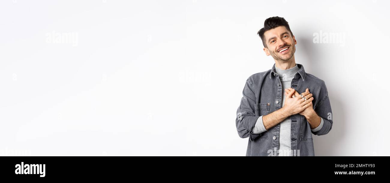 Romantic guy hold hands on heart and smiling, thanking you, looking ...