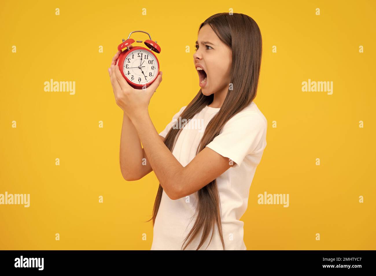 Punctual teen girl checking time. Child with alarm clock showing time ...