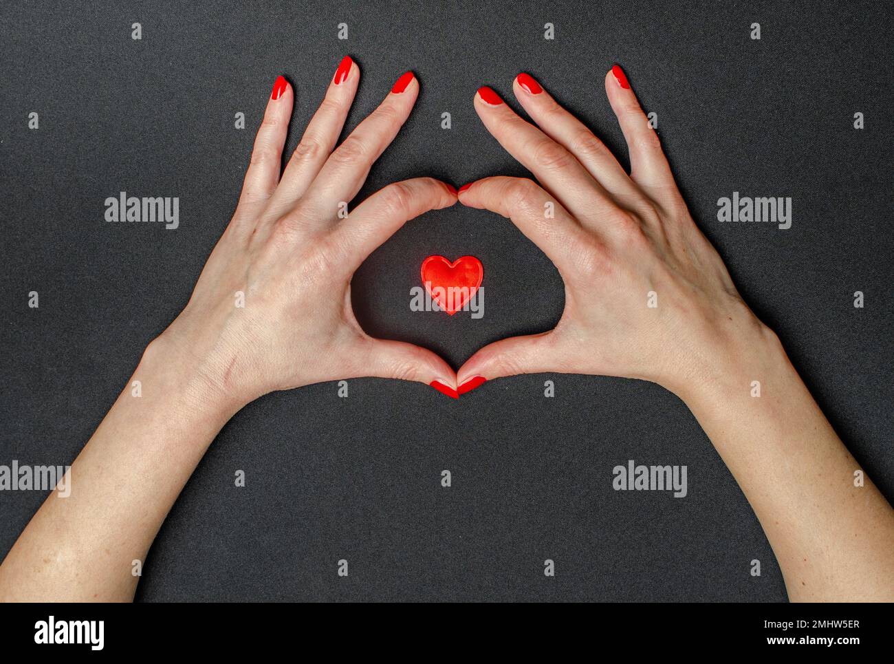Female hands around red heart. Love. Black background Stock Photo - Alamy