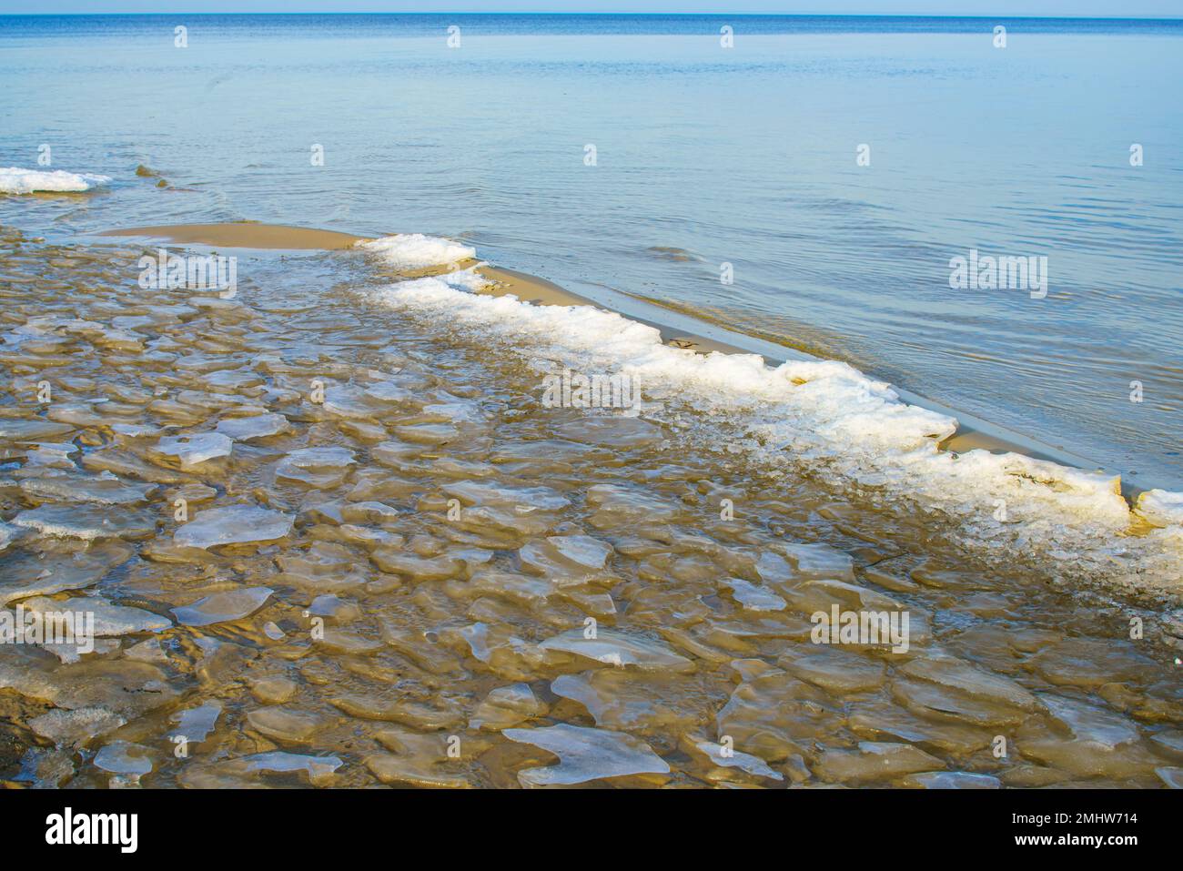 Natural background, sandy shore with ice and water. View of the winter ...