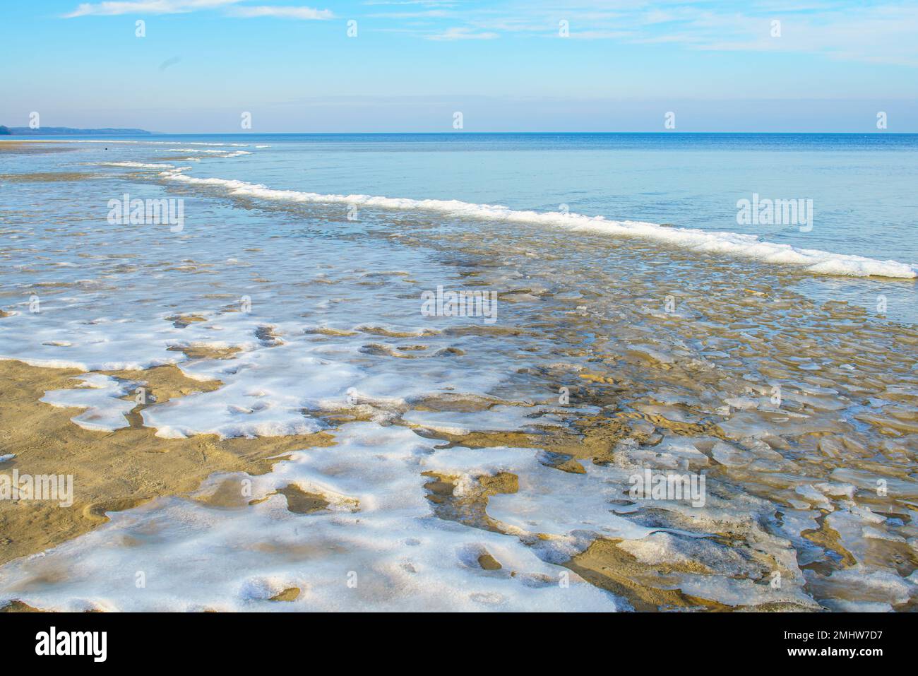 Natural background, sandy shore with ice and water. View of the winter ...