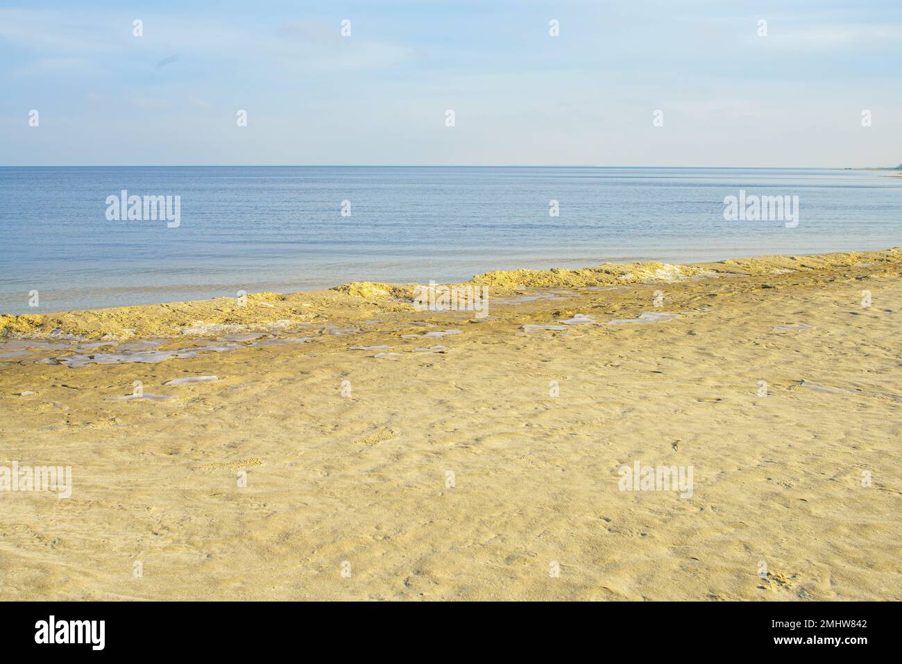 Natural background, sandy shore with ice and water. View of the winter ...