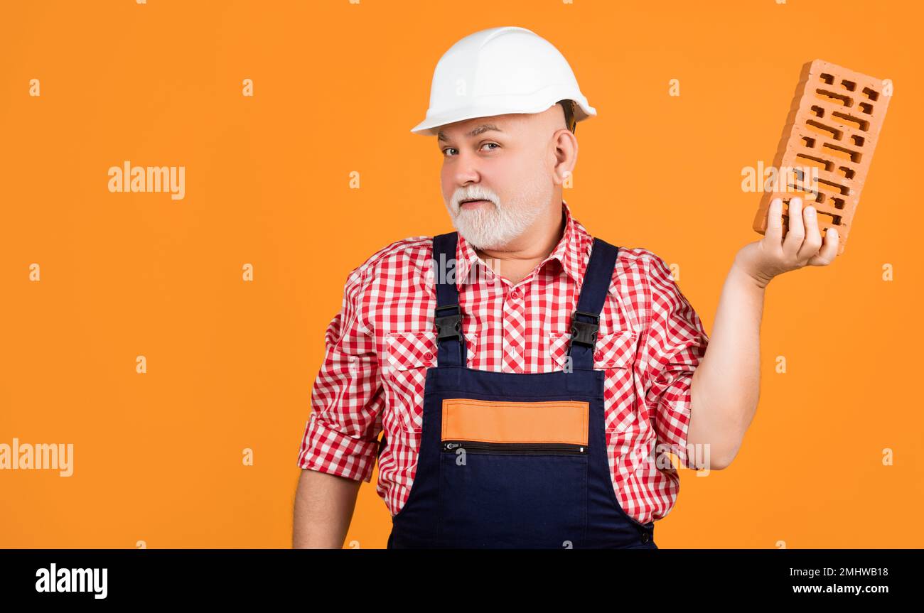 serious old man bricklayer in helmet on yellow background Stock Photo ...