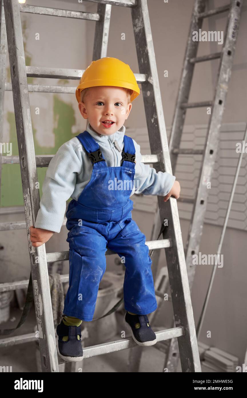 Child builder sitting on ladder in apartment under renovation. Adorable ...