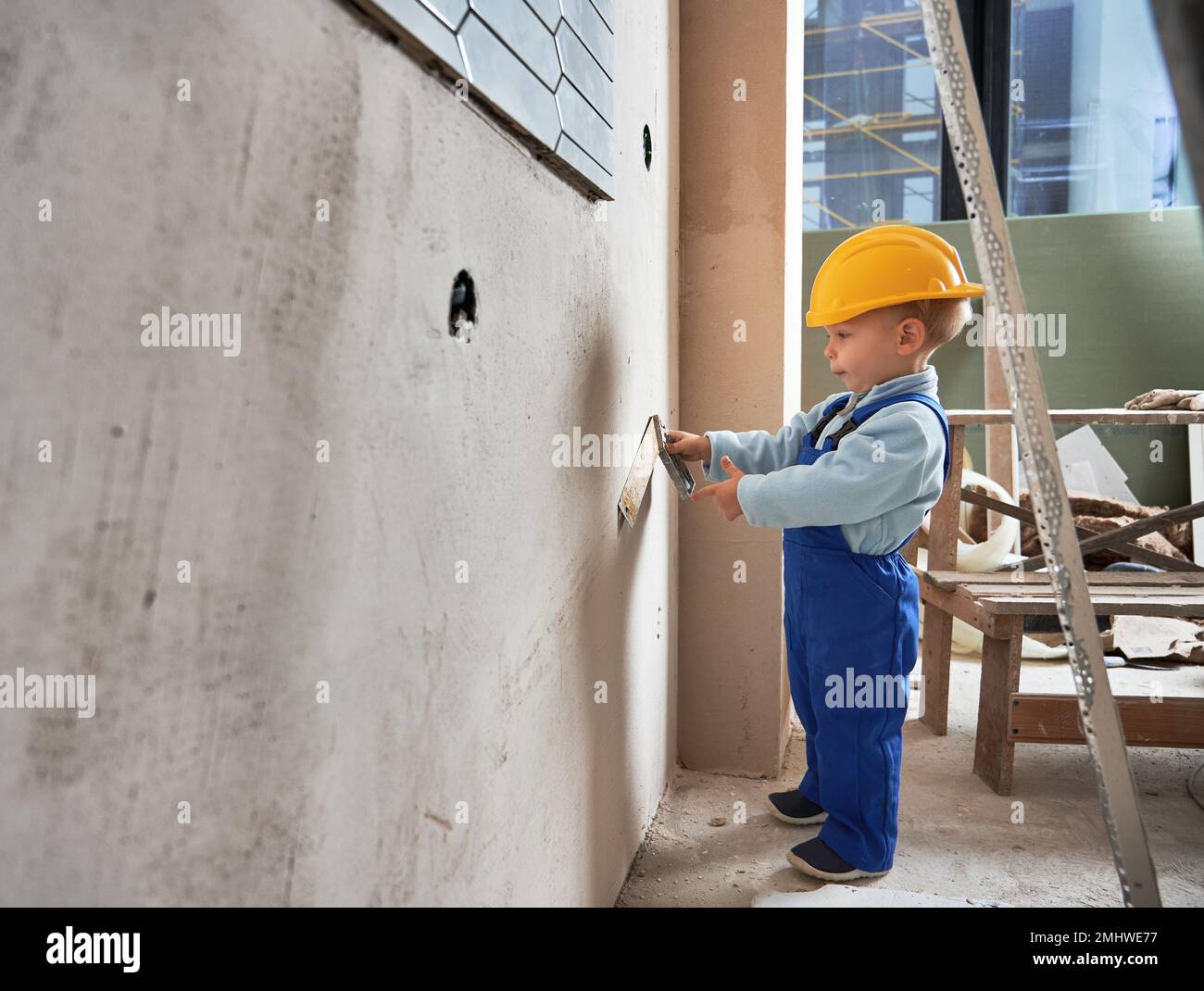 Little boy builder worker measuring wall with construction ruler ...
