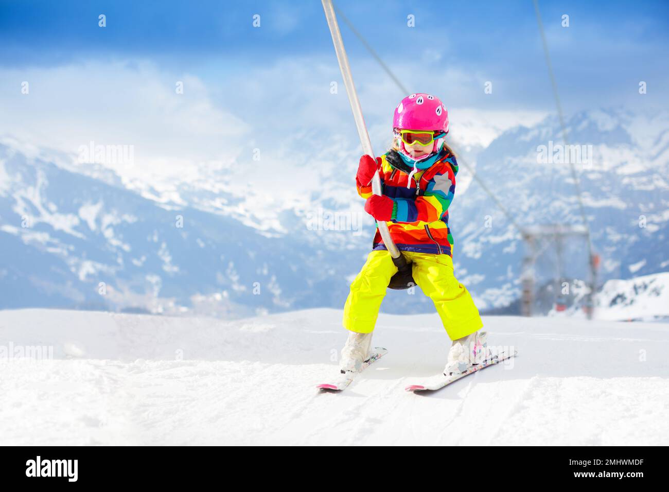 Child on a button ski lift going uphill in the mountains on a sunny ...