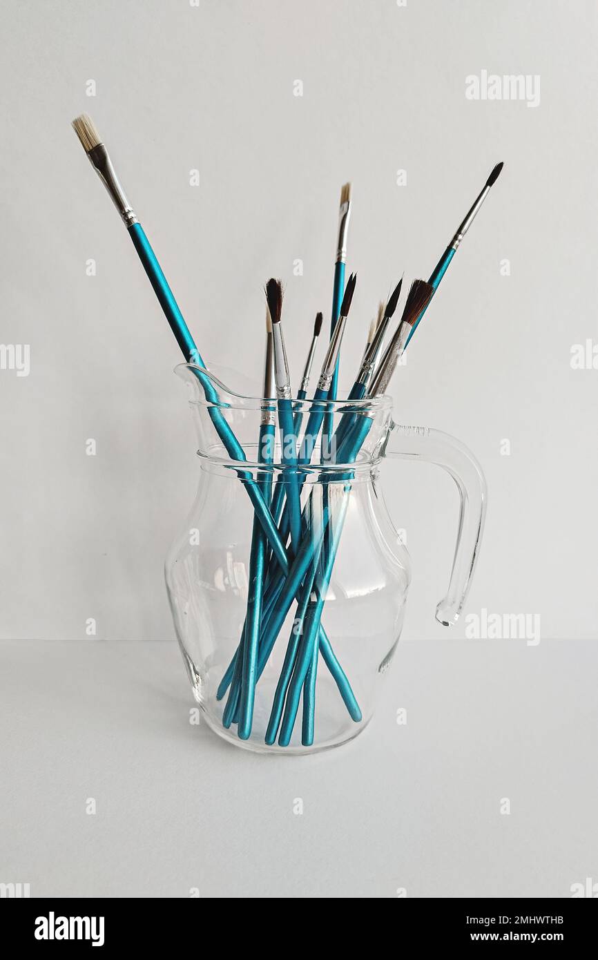 Glass pot with lots of brushes against a white background in an art ...