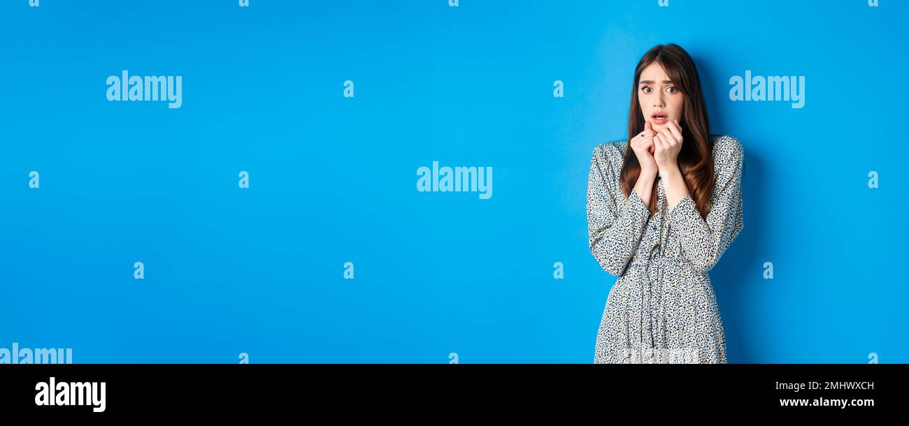 Scared and timid woman in dress, shaking from fear, gasping with hands ...
