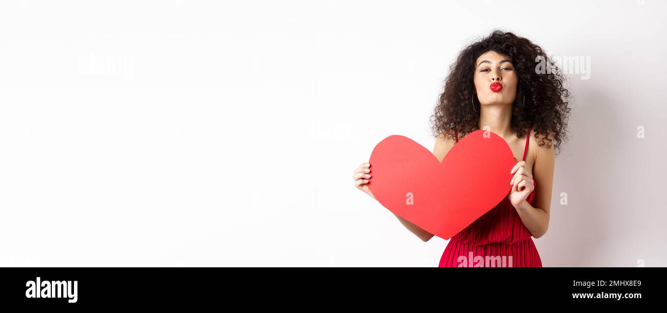 Romantic woman in dress showing big red heart, pucker lips for kiss and ...