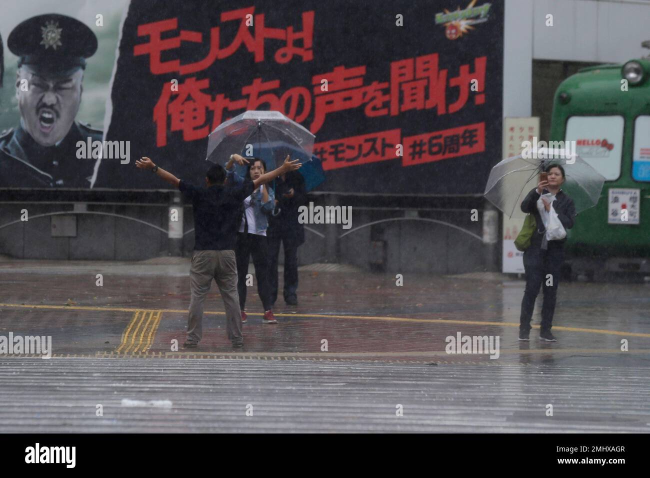A man poses for picture in rain at a crossing in Shibuya district ...
