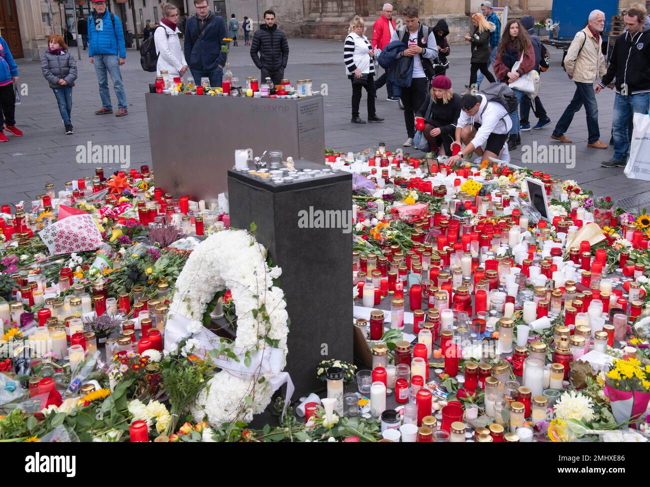 People place down flowers and candles at the marketplace in the old ...