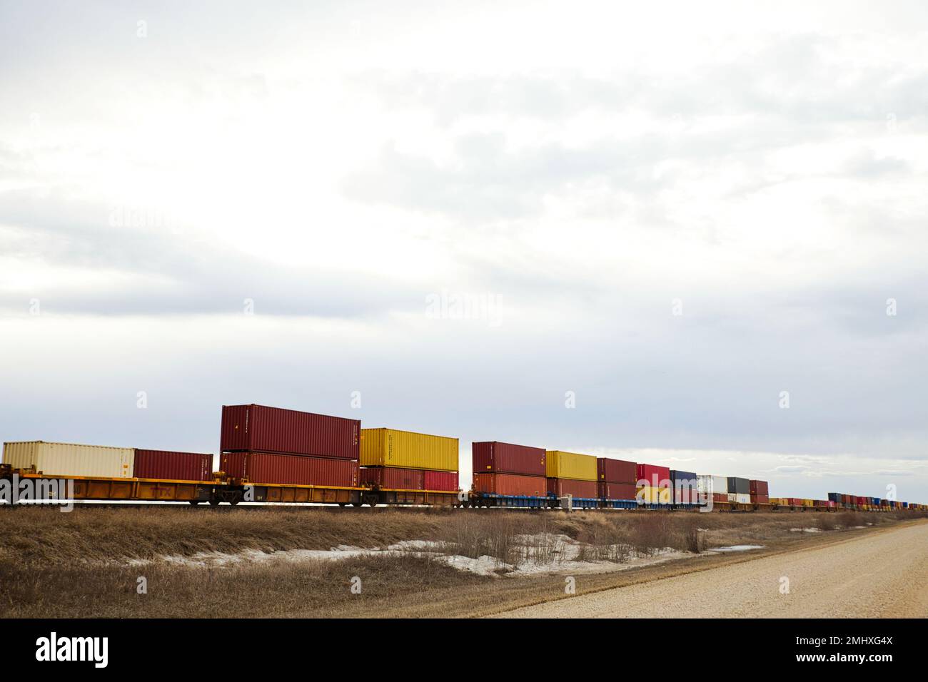 Red, orange and yellow box cars on a flat bed along a railroad track ...
