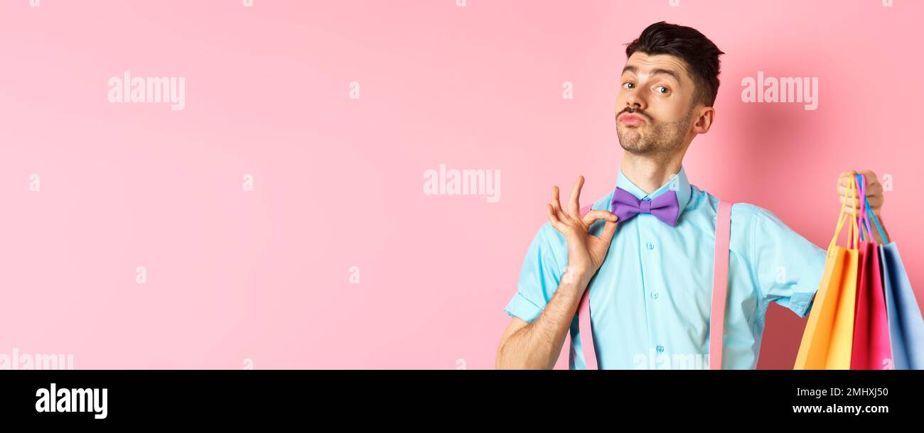 Fancy guy with moustache fixing his bow-tie and holding shopping bags ...