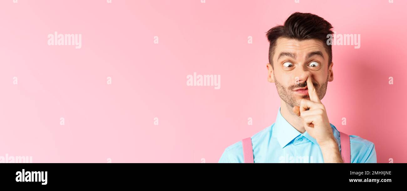 Image of funny caucasian guy picking nose and squint eyes, making dumb ...