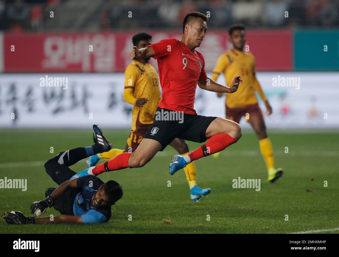 South Korea's Kim Shin-wook, center, jumps over Sri Lanka's goalkeeper ...