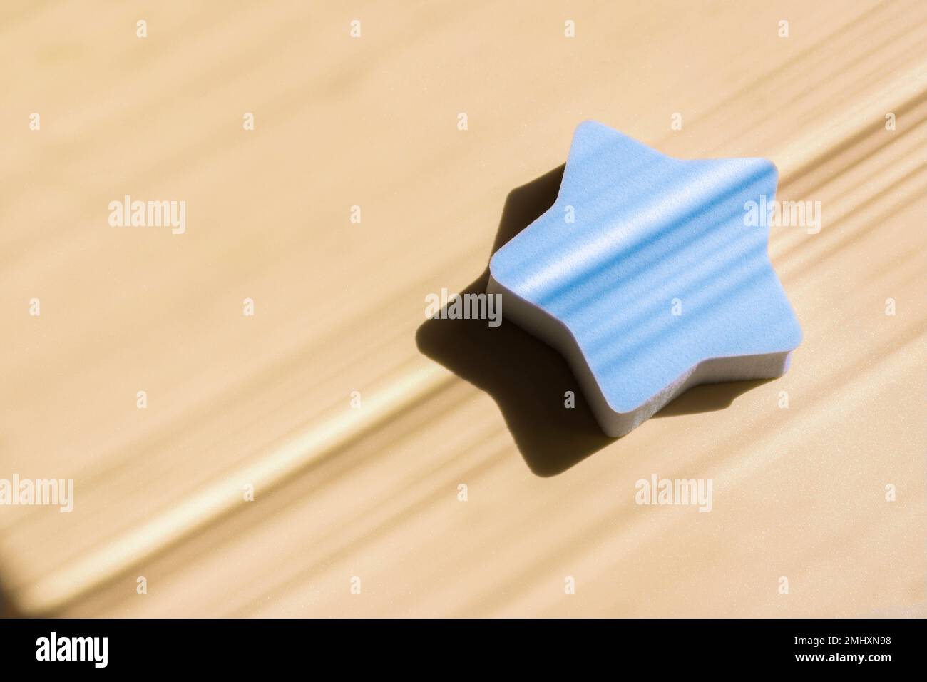 Blue cosmetic sponge in the shape of a star on a beige background with ...