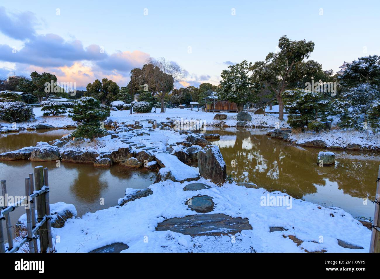 Dawn in Japanese garden with stone path and bridge through snow over ...