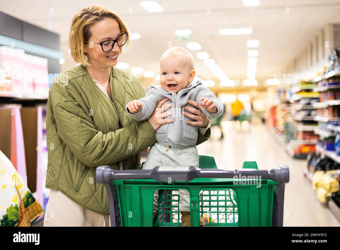 Mother pushing shopping cart with her infant baby boy child down ...