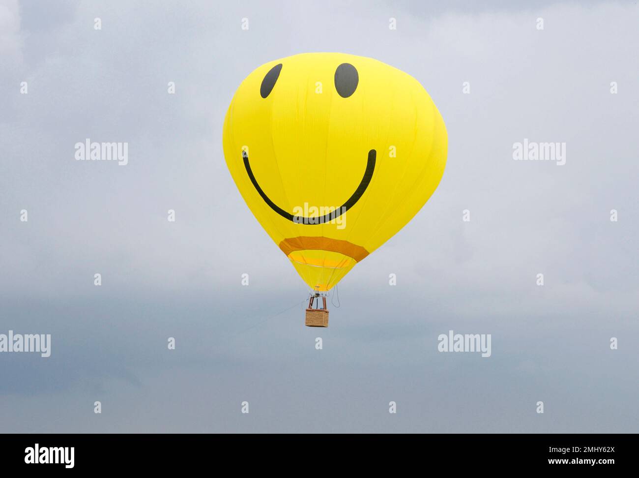 Yellow balloon with the smiley face symbol on it flying in the cloudy ...