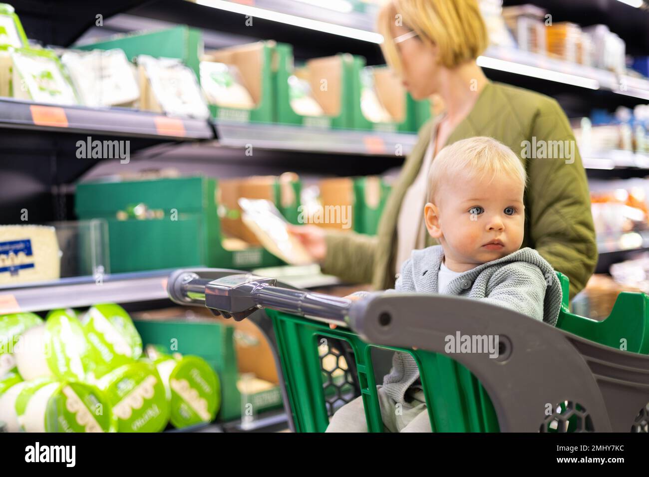 Casualy dressed mother choosing products in department of supermarket ...