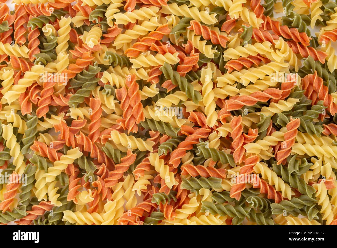 Raw colored pasta fusilli. Uncooked pastas background. Top view Stock ...