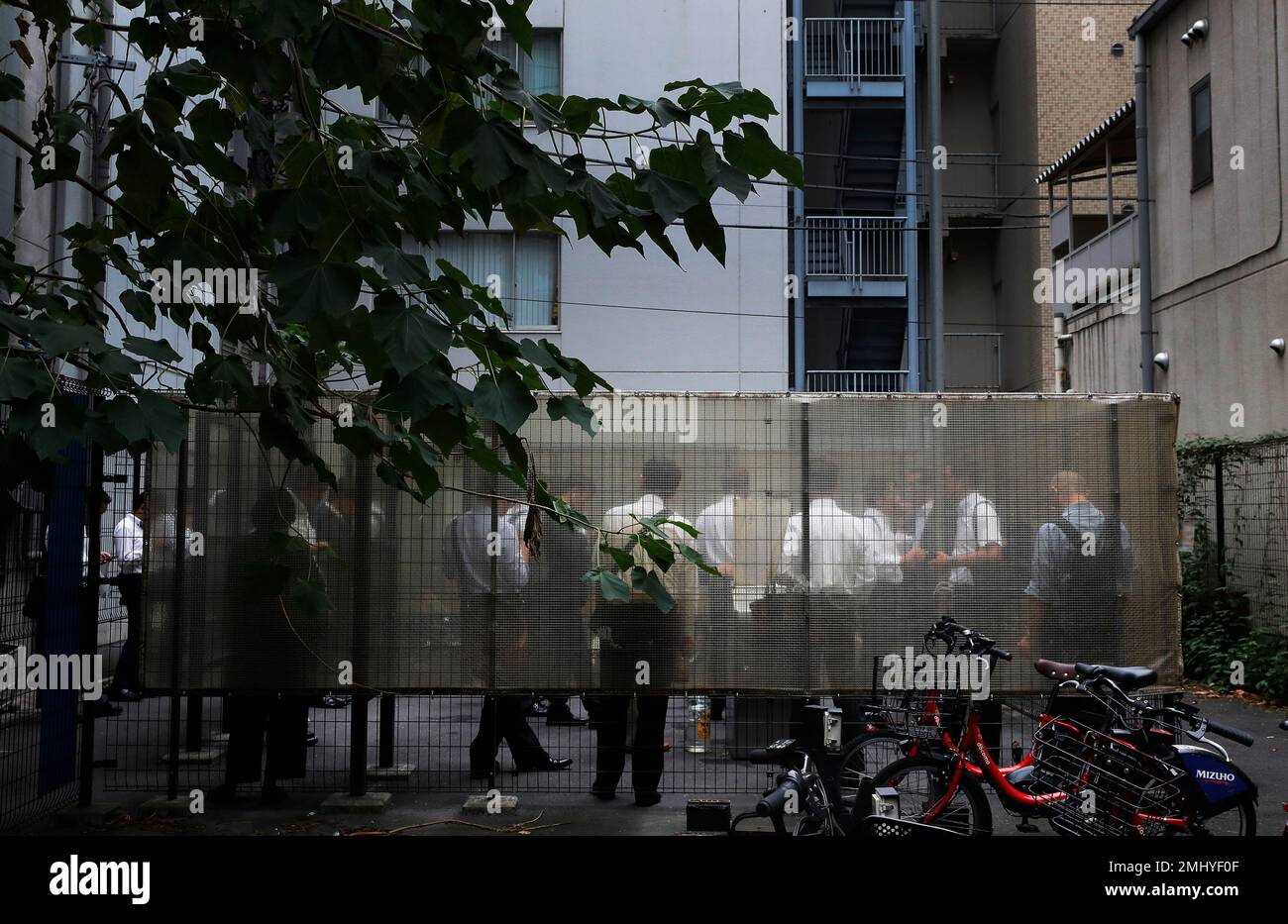 Men smoke in a designated smoking area in Tokyo, Japan, Monday, Oct. 7 ...