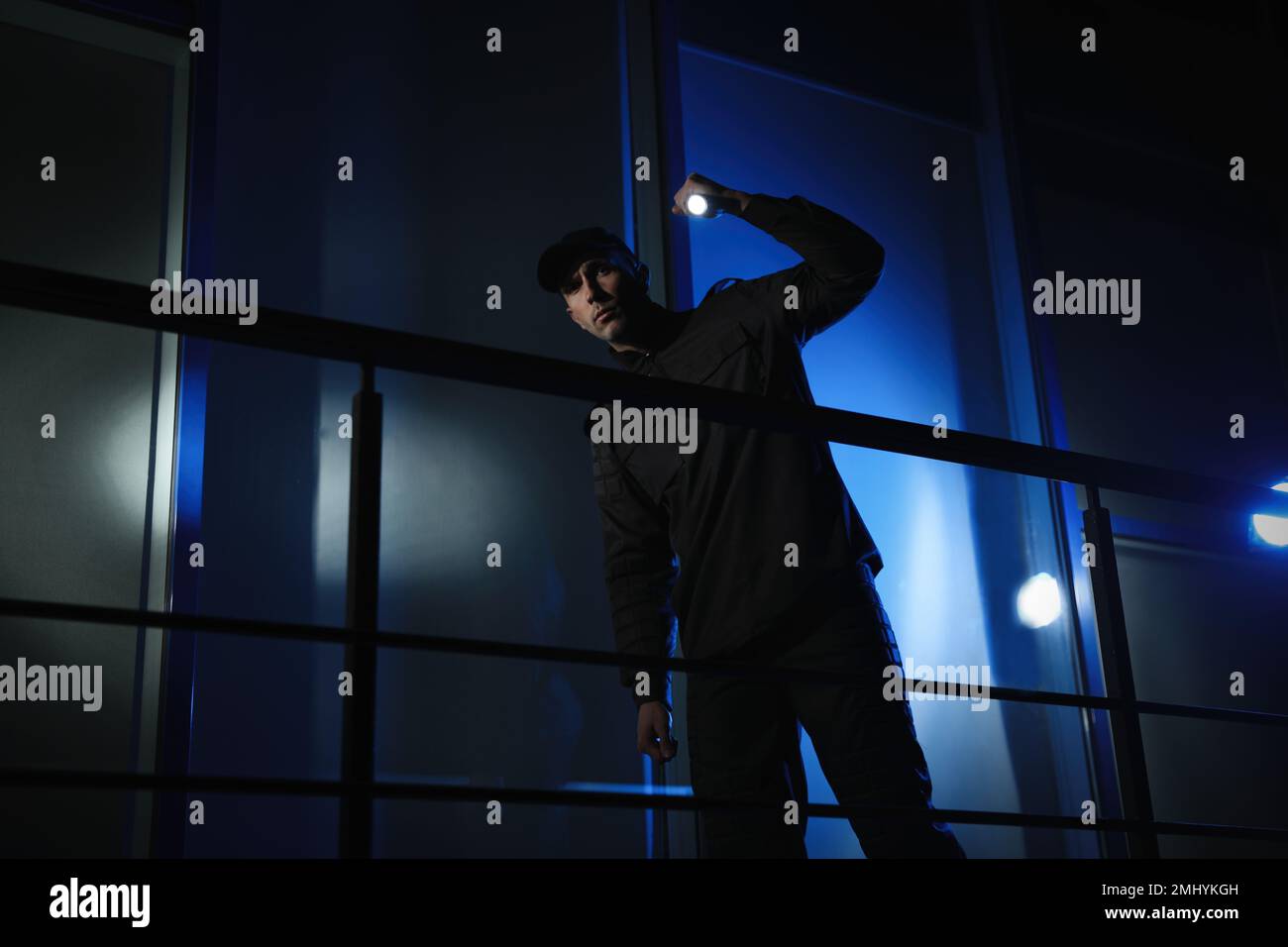Male security guard with flashlight in dark room Stock Photo - Alamy