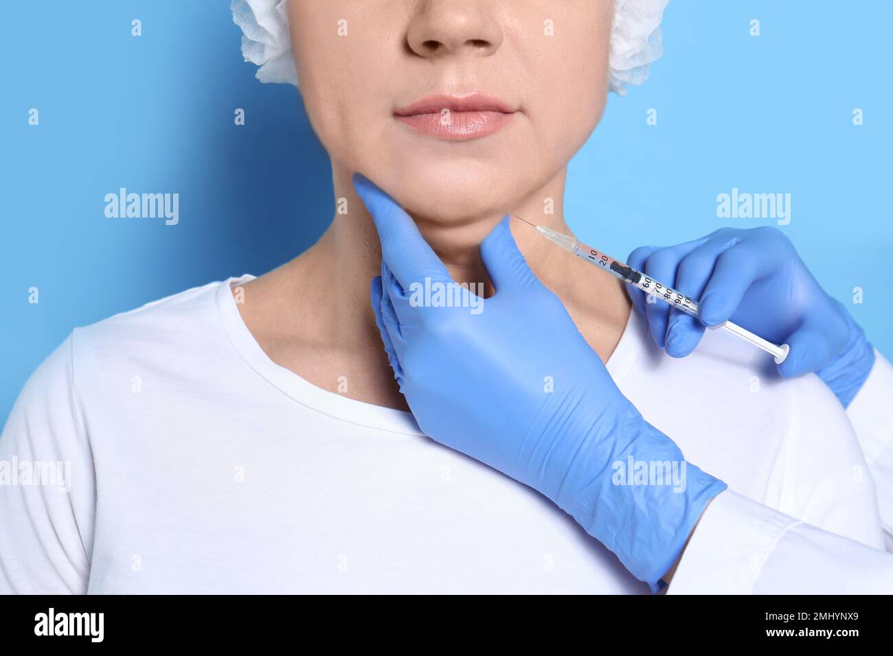 Mature woman with double chin receiving injection on blue background ...