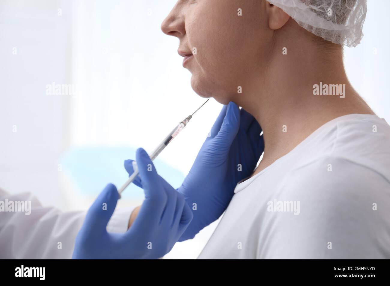 Mature woman with double chin receiving injection in clinic, closeup ...