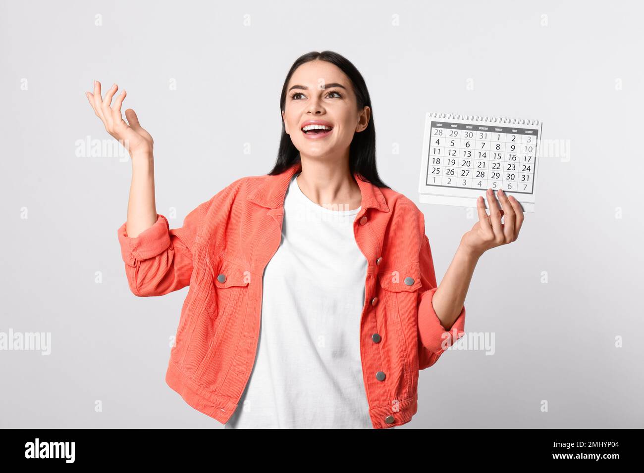 Emotional young woman holding calendar with marked menstrual cycle days ...