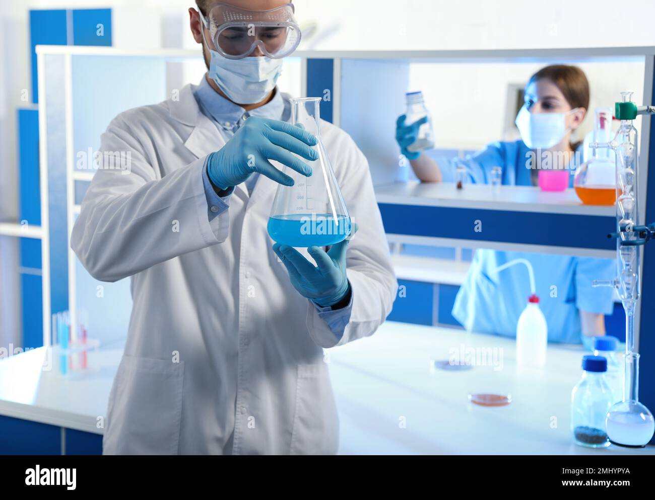 Scientist holding conical flask with blue liquid indoors. Laboratory ...