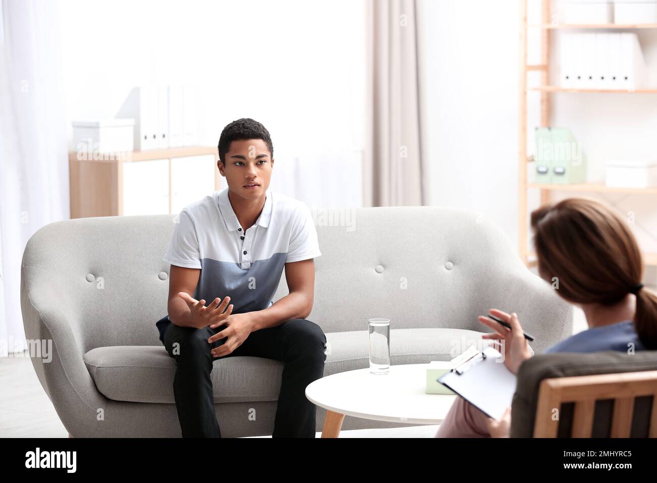 Psychotherapist working with African-American teenage boy in office ...