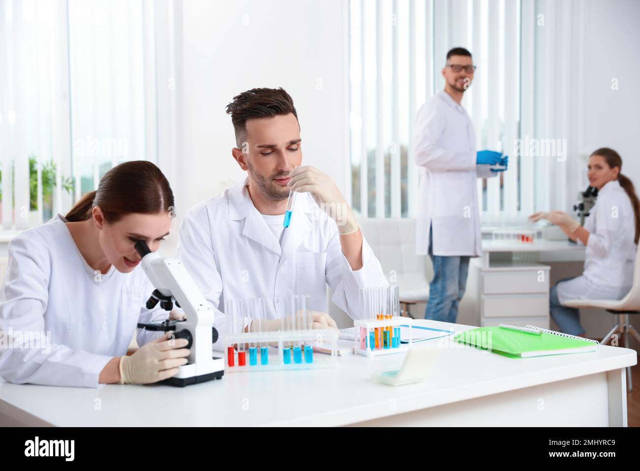 Scientist with microscope and colleagues in laboratory. Medical ...