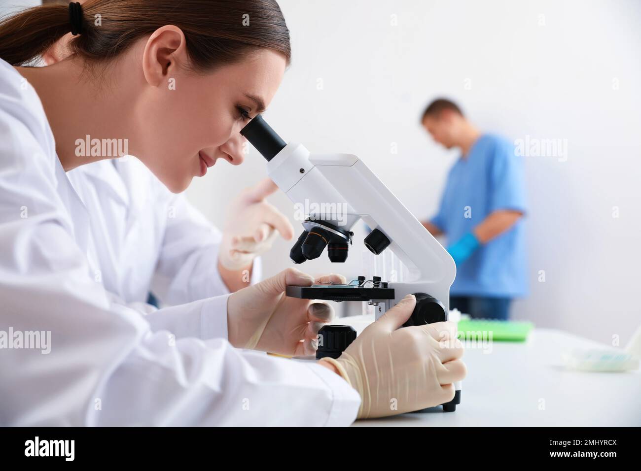 Scientist with microscope and colleagues in laboratory, closeup ...