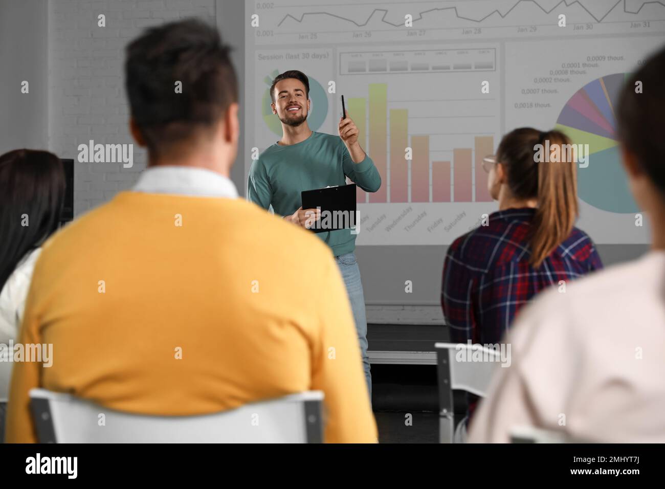 Male business trainer giving lecture in conference room with projection ...